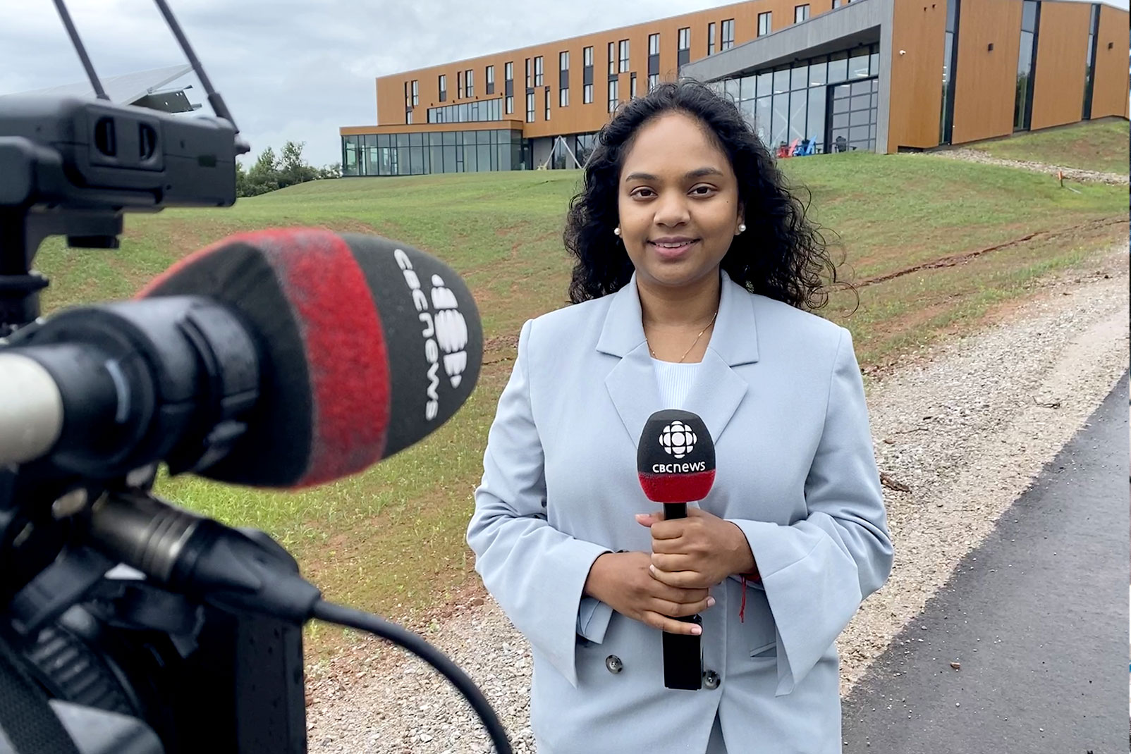 A female journalist holding a microphone while being filmed on set