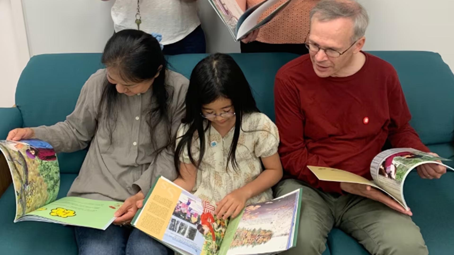 A diverse group of five people is holding large books in their hands ...