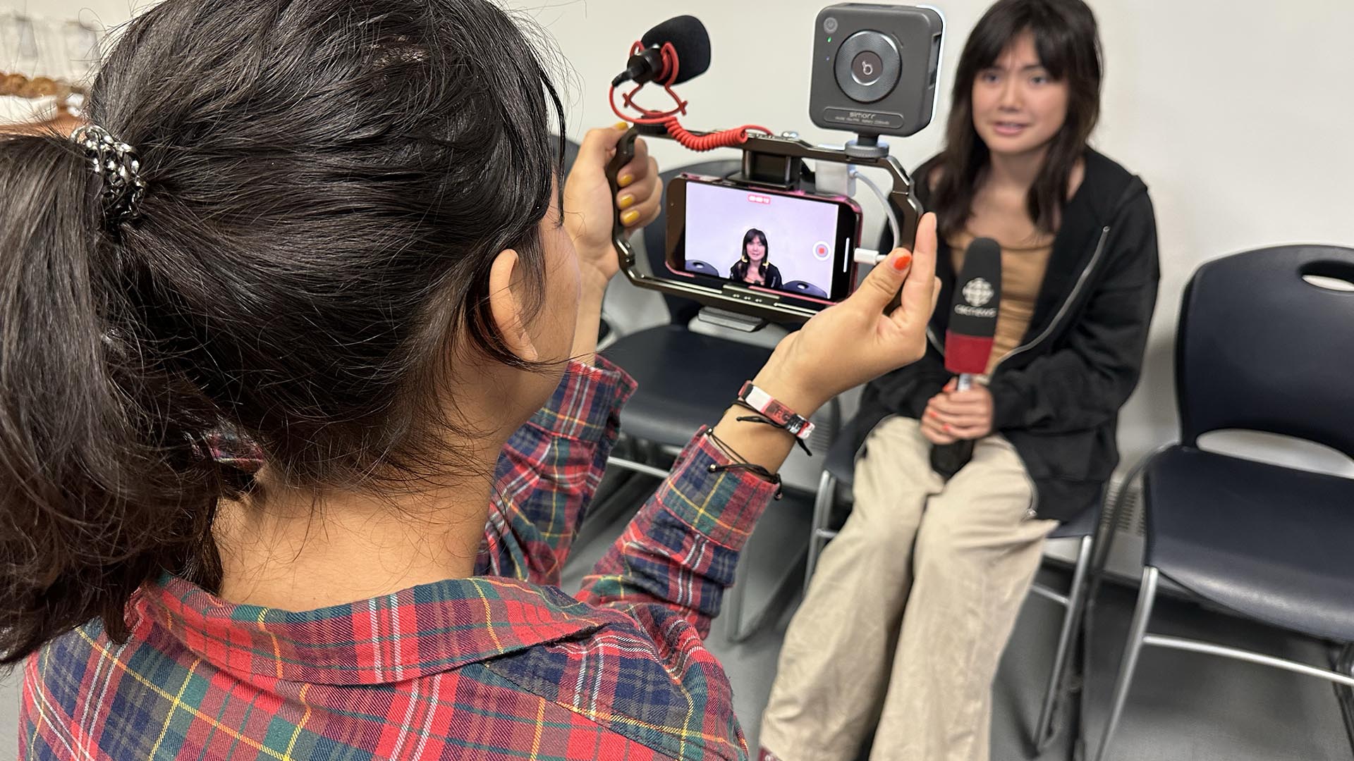 A girl is holding a camera, recording a video of another girl talking ...