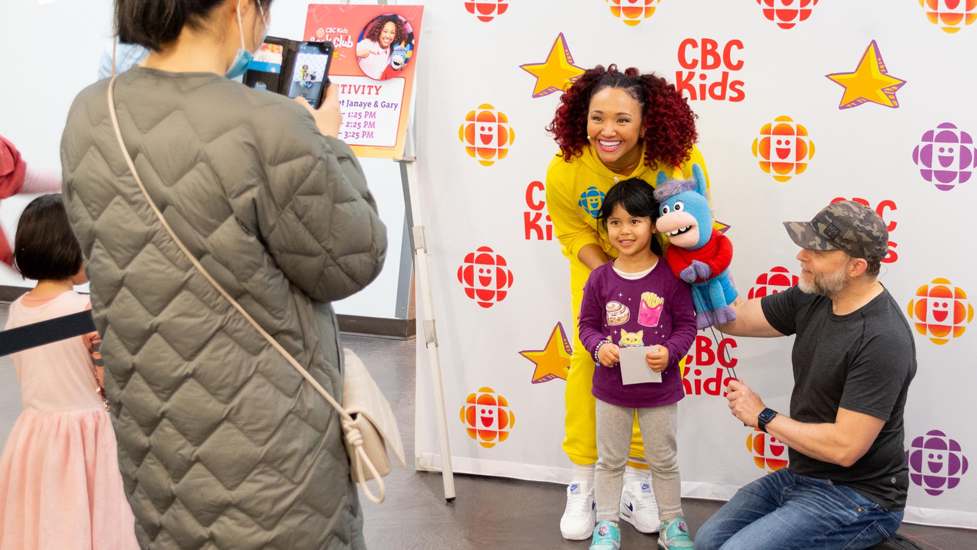 A woman is taking a picture of a little girl together with the CBC Kids ...