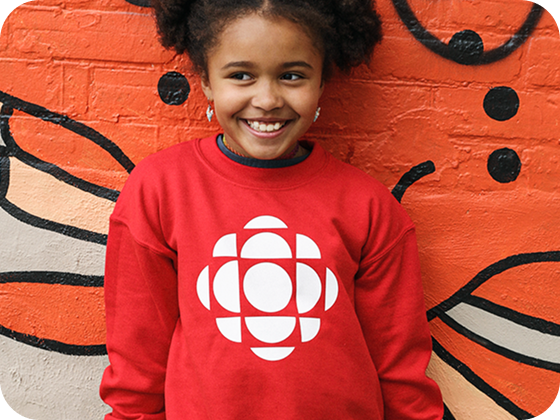 A young girl in a red sweatshirt with a CBC/Radio-Canada white logo ...