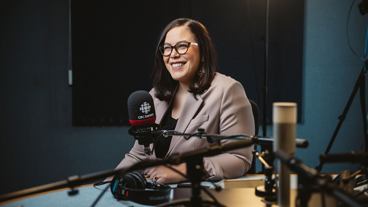 A woman smilling behind a radio microphone.